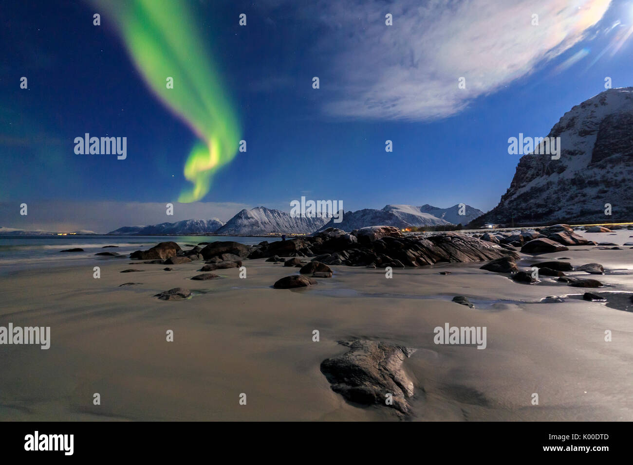 The aurora borealis lights up the sky and the beach of the cold sea of ...