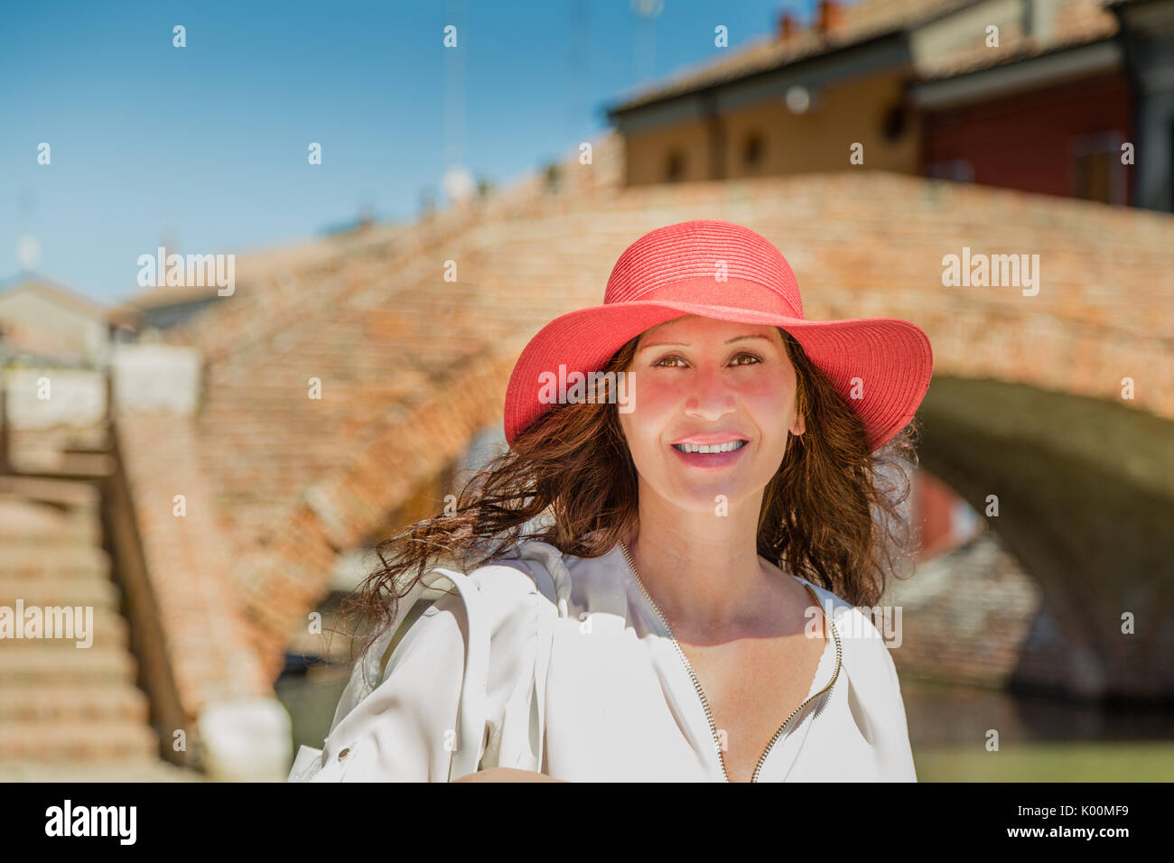 Smiling menopausal tourist with red wide hat enjoying ancient lagoon ...