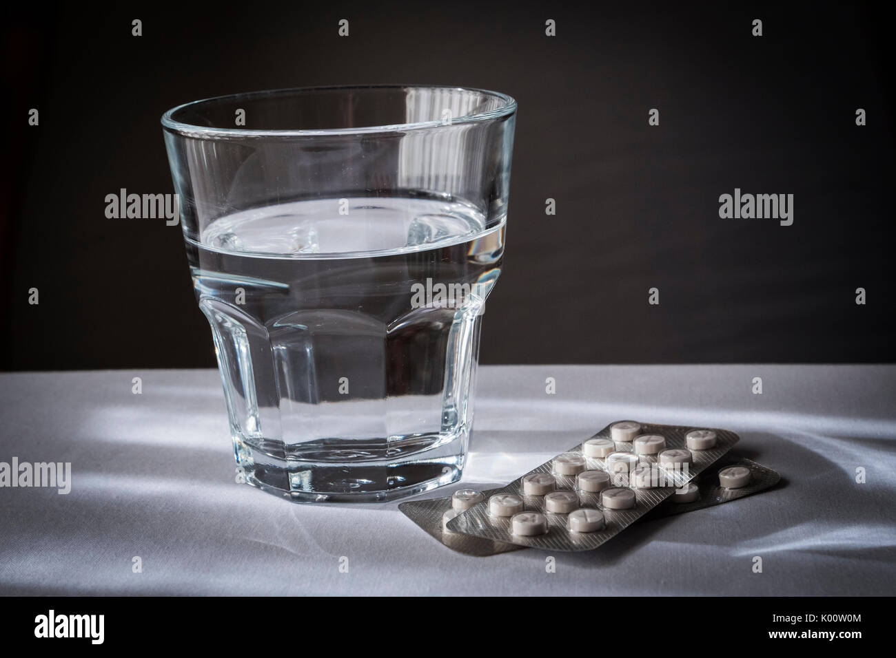 Some pills of different size and color along with a water glass Stock ...