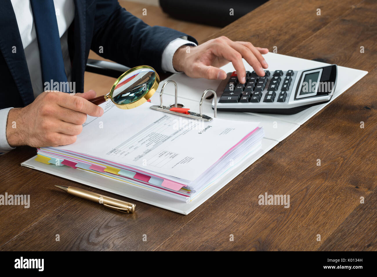 Cropped image of businessman checking invoice with magnifying glass at ...