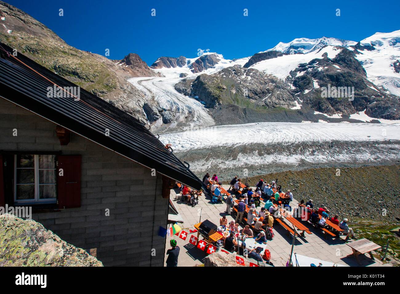 Hikers resting on the terrace of the Chamanna Boval Hut, enjoying the ...