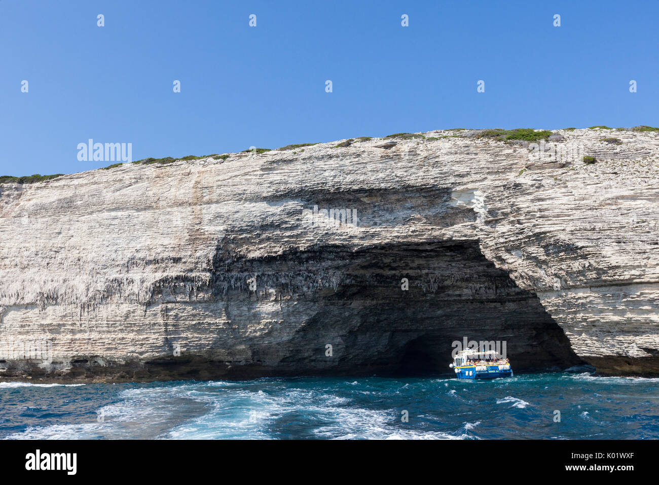 A tourist boat framed by granite white cliffs and sea caves Lavezzi ...