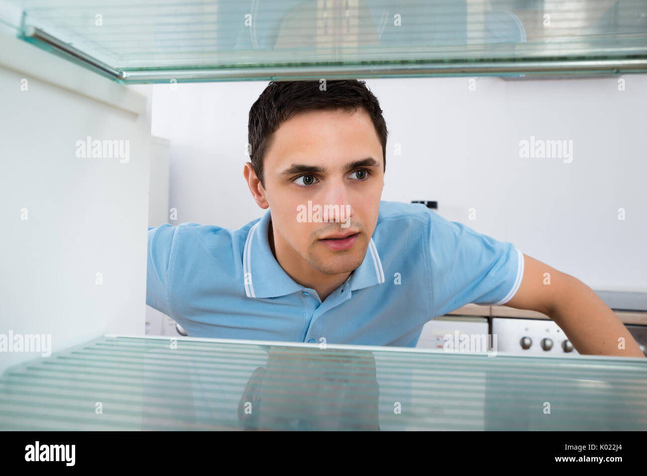 Shocked young man looking into empty refrigerator at home Stock Photo ...