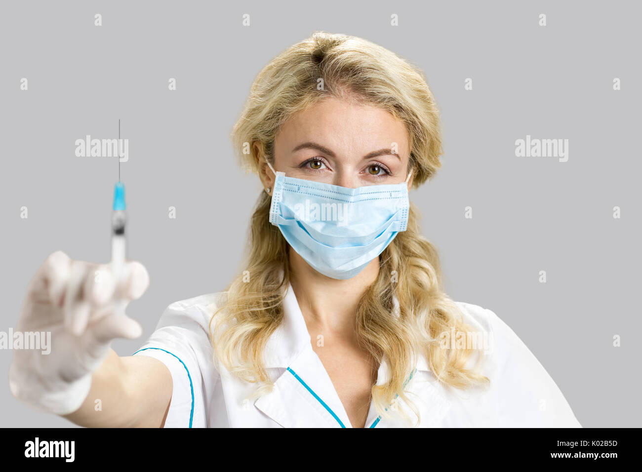 Young female doctor or nurse in surgical mask holding an injection in ...
