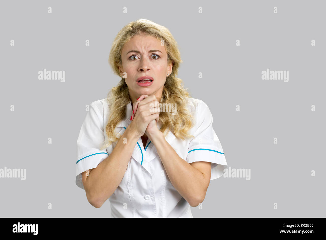 Shocked young nurse clasped hands. Beautiful young medical doctor or ...