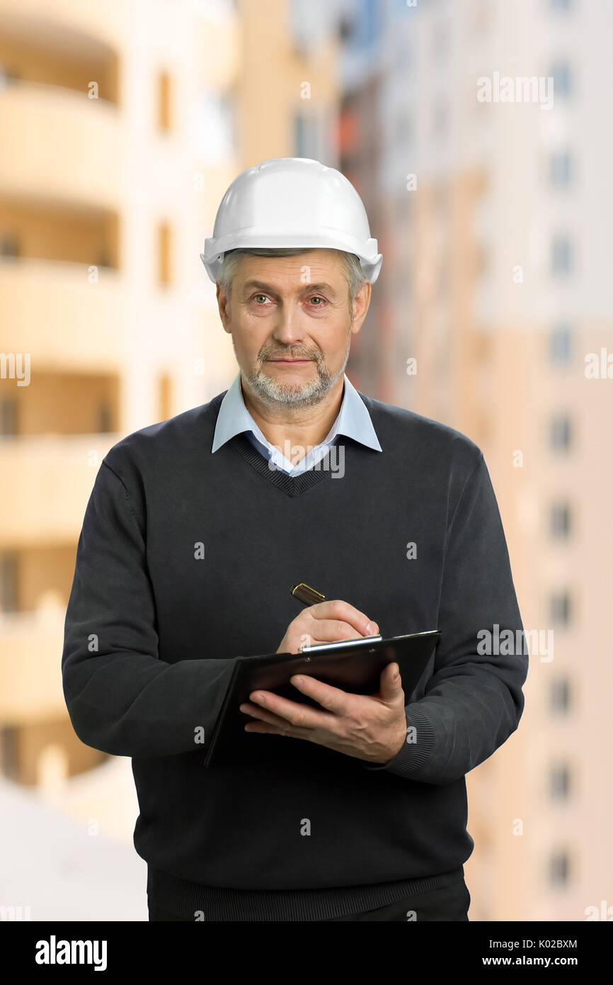 Mature engineer on blurred background. Senior architect writing on ...