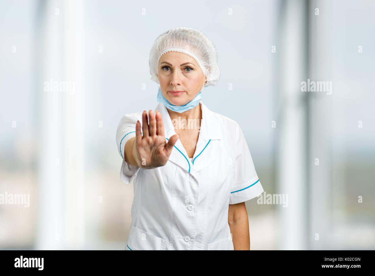 Mature female surgeon gesturing stop. Confident medical doctor woman ...