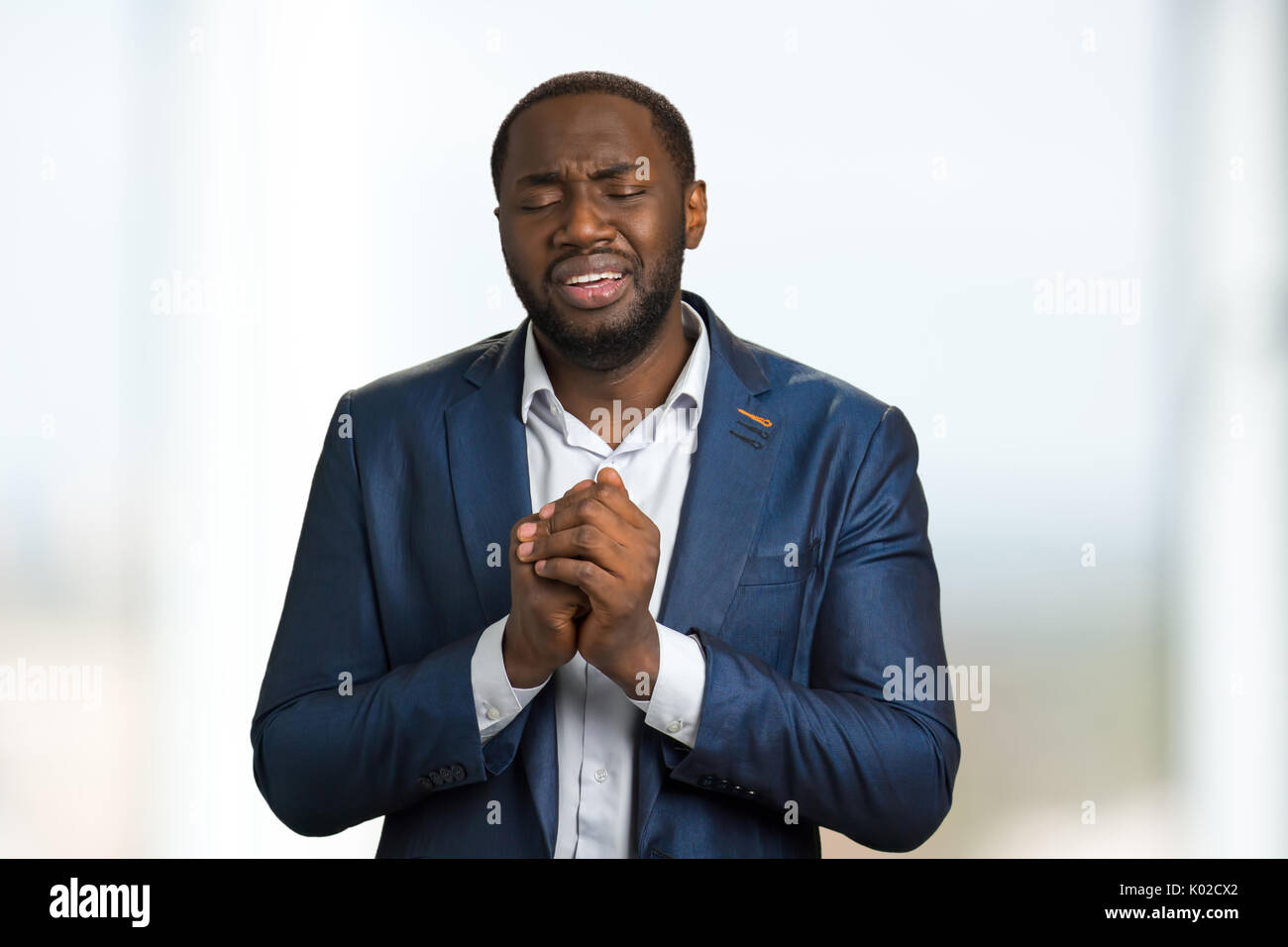 Worried businessman with closed eyes. Dark skinned manager with clasped ...