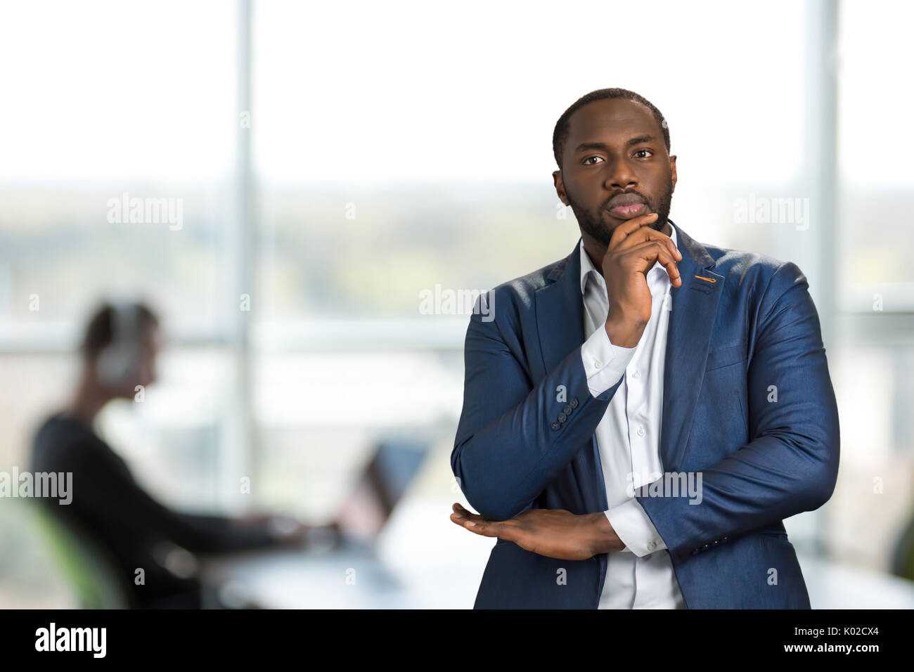 Serious businessman hold chin on hand. Handsome young manager thinking ...