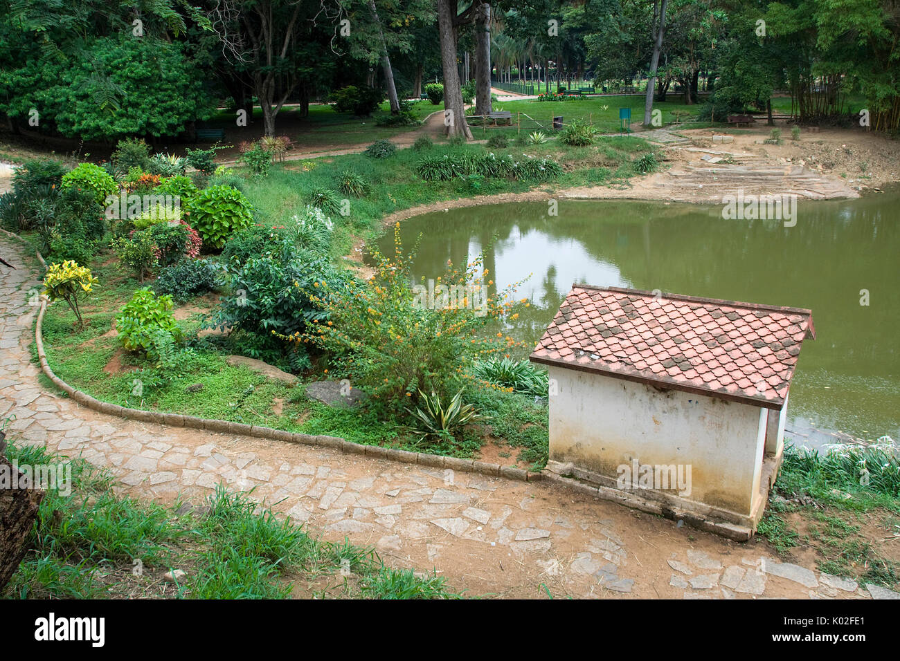 Pond of water surrounded by green landscaped bund and a tile-roofed ...