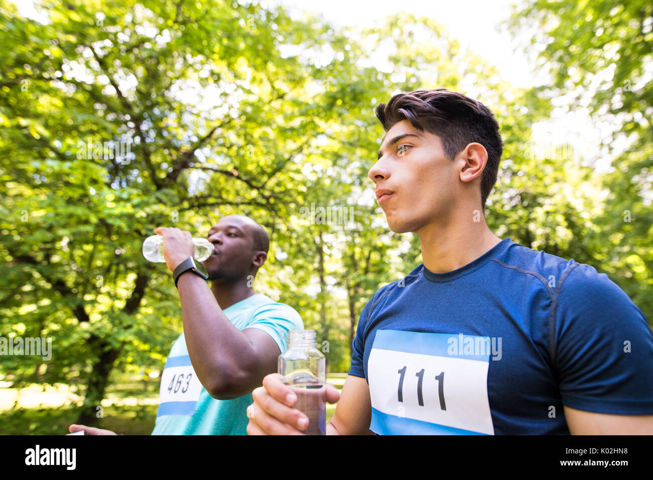 Two young athletes prepared for run, drinking water Stock Photo - Alamy