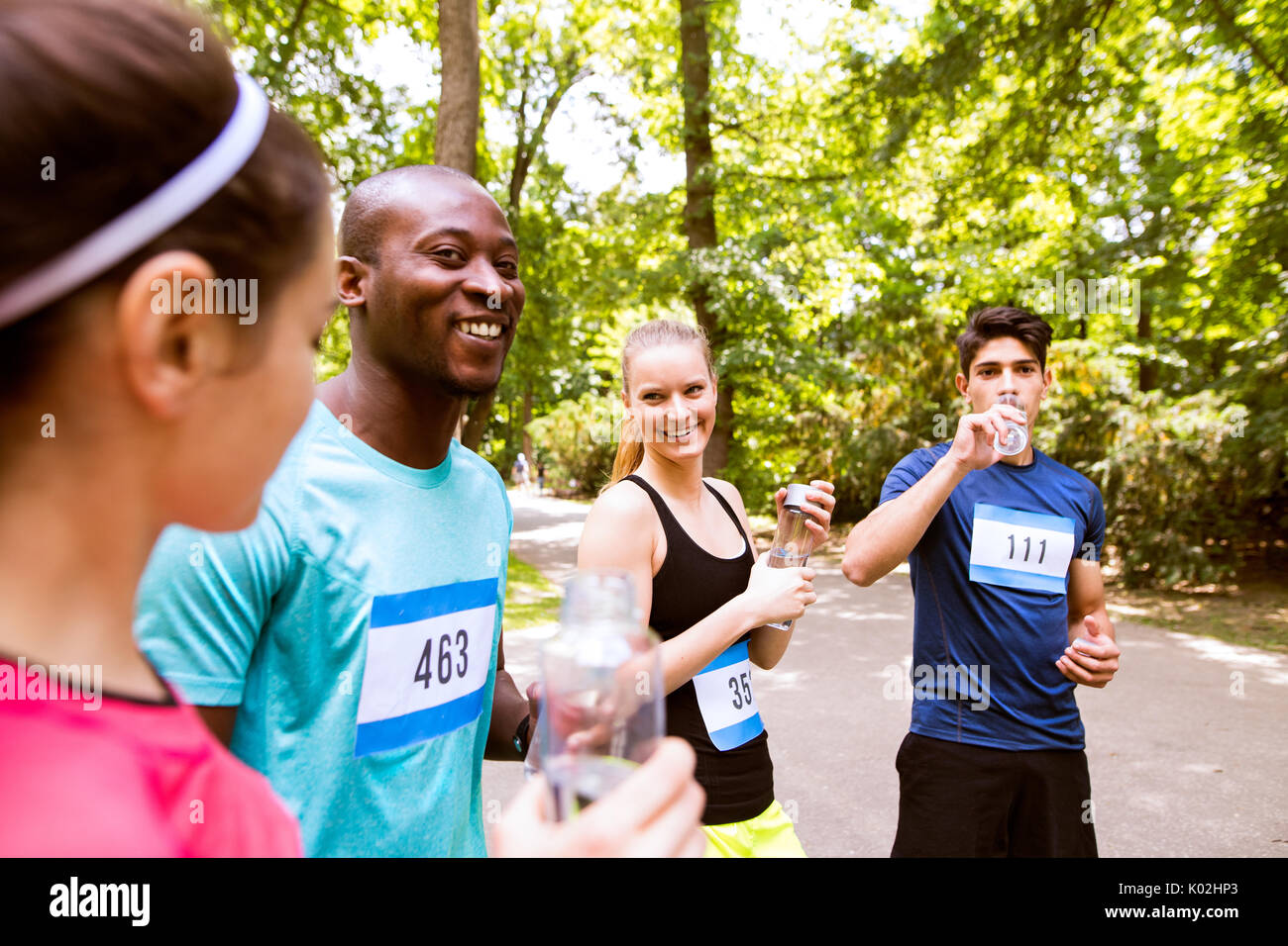 Group of young athletes prepared for run, drinking water Stock Photo ...