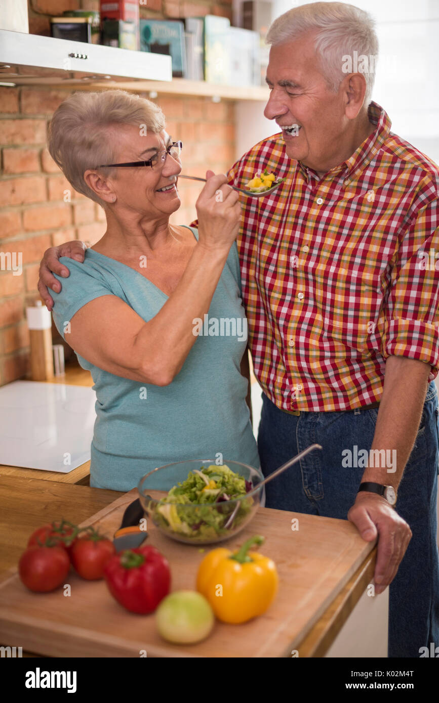 Husband sampling a homemade vegetable salad Stock Photo - Alamy