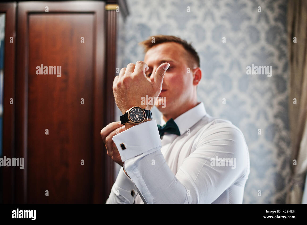 Portrait of a stunning groom dressing up for the wedding and getting ...