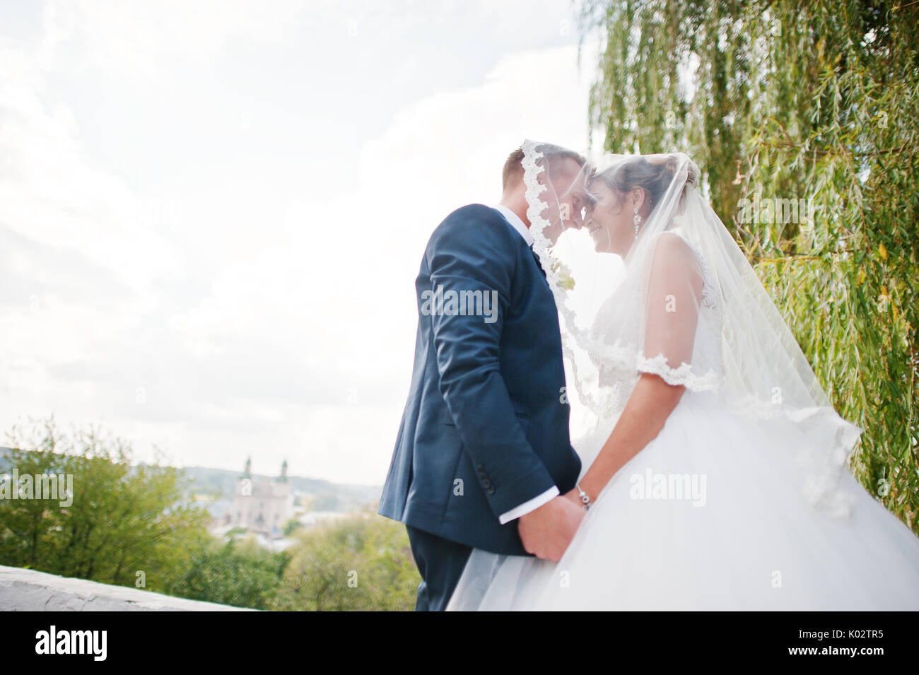 Good-looking newly married couple looking into each other's eyes under ...