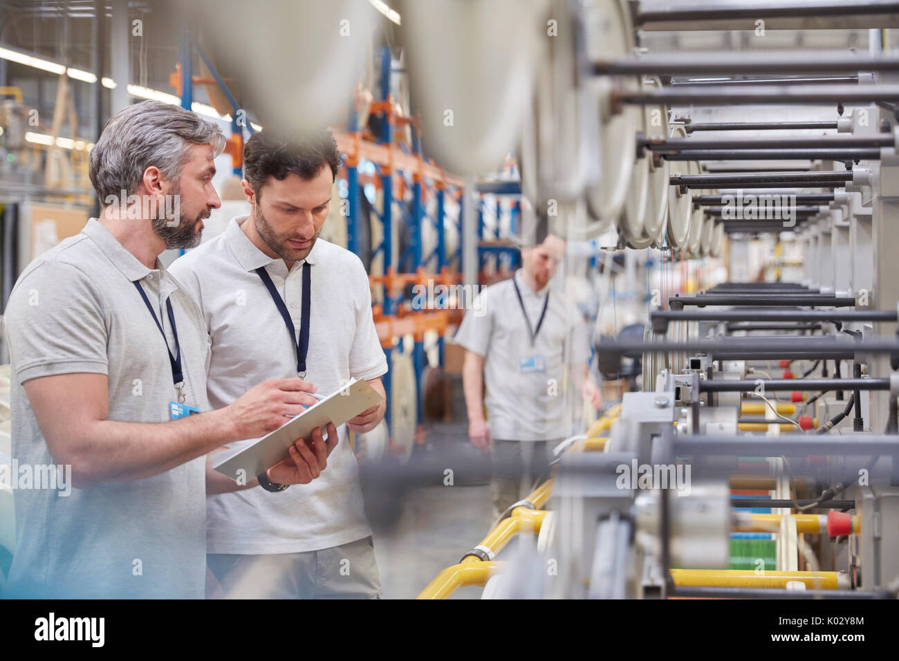 Male supervisor and worker with clipboard talking in fiber optics ...