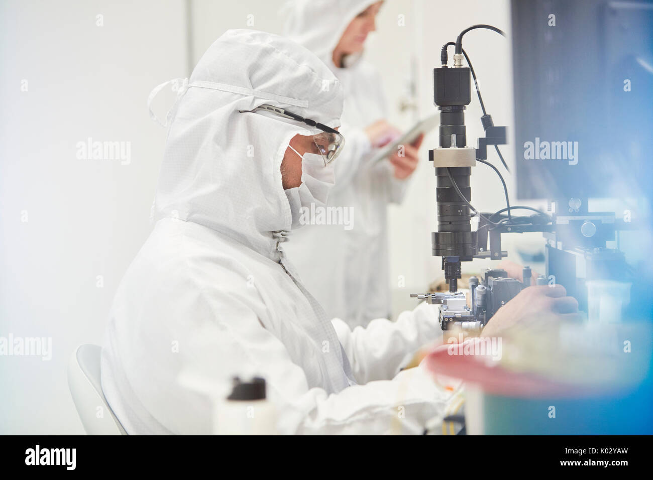 Workers in protective suits using machinery in fiber optics research ...