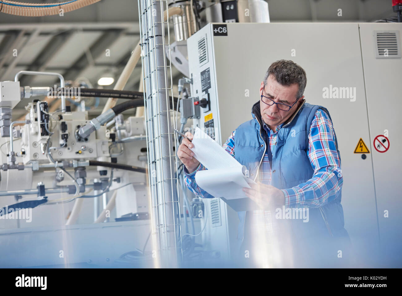 Male supervisor with clipboard talking on cell phone in factory Stock ...