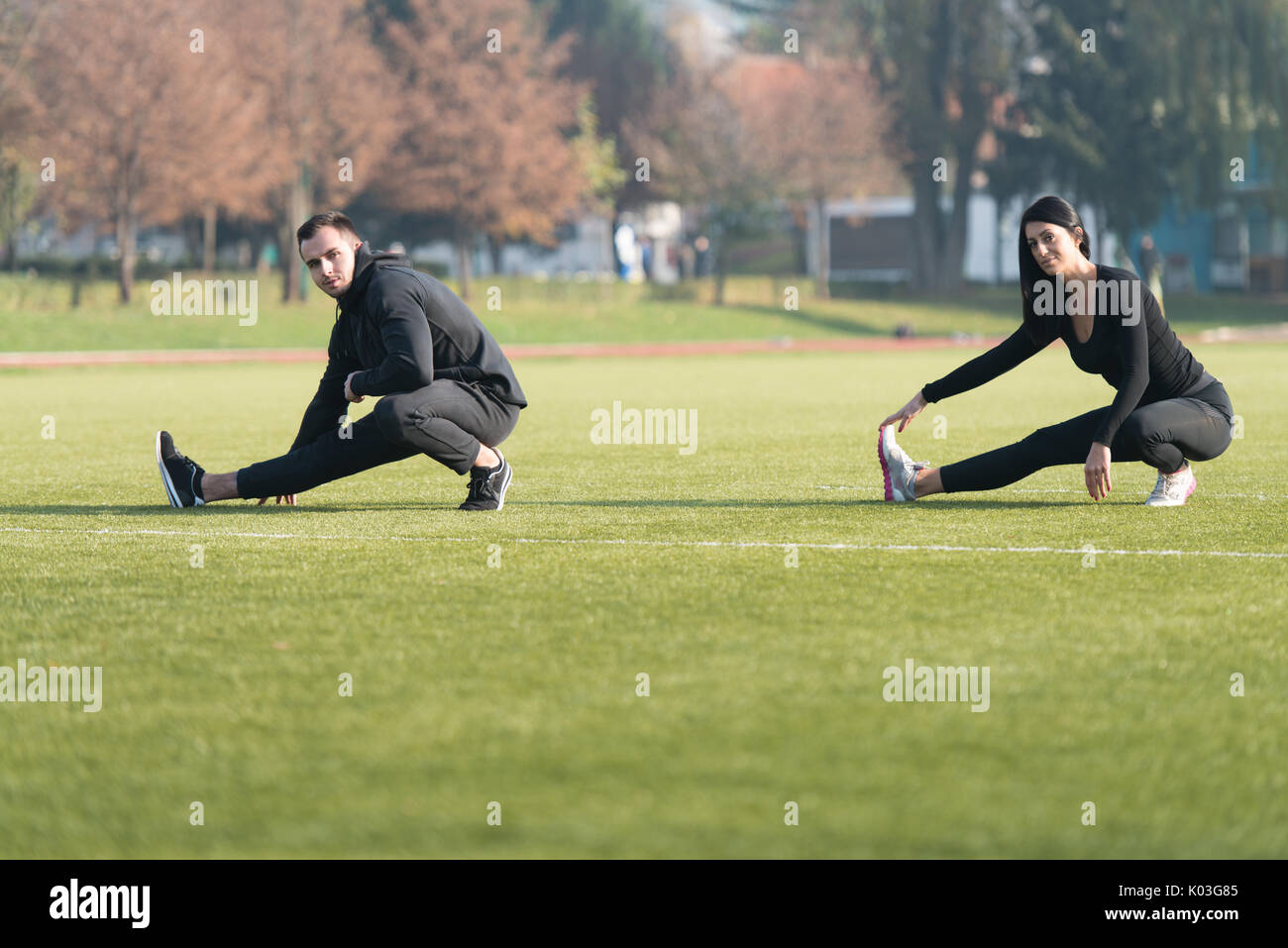 Young Couple Stretching Before Running In City Park Area - Training And ...