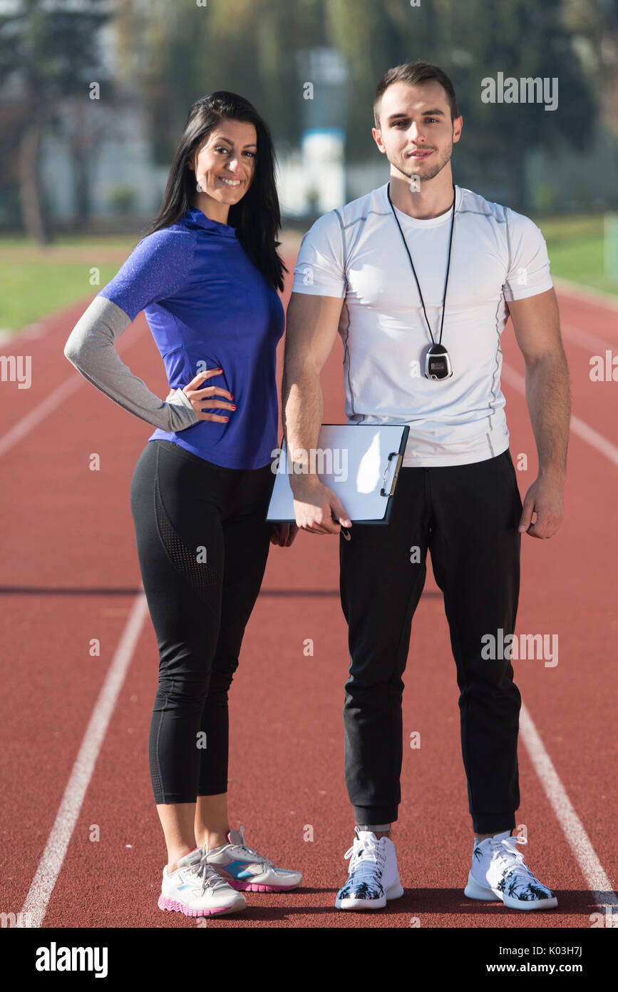 Personal Trainer Takes Notes While Young Woman Exercise in City Park ...
