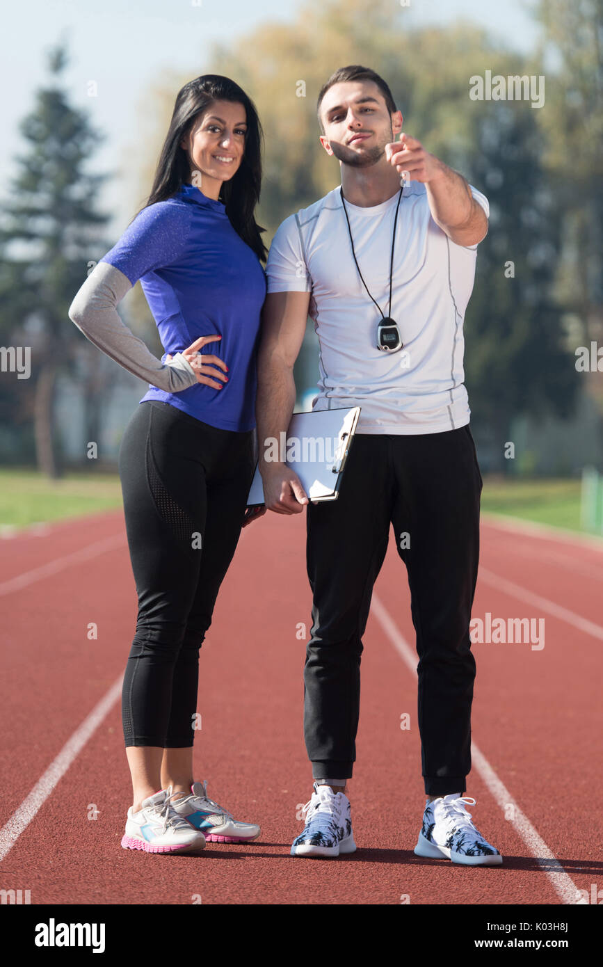 Personal Trainer Takes Notes While Young Woman Exercise in City Park ...
