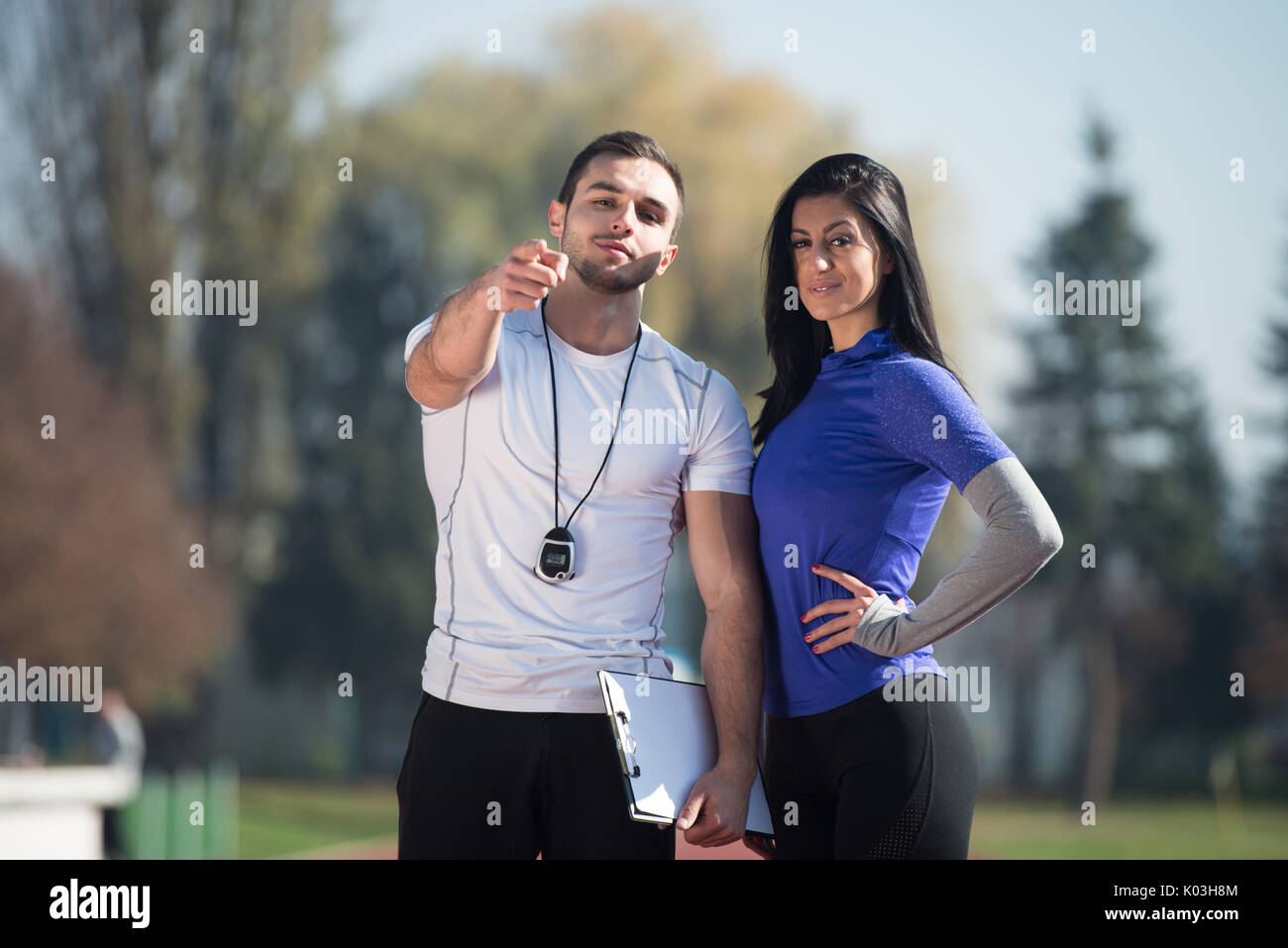 Personal Trainer Takes Notes While Young Woman Exercise in City Park ...