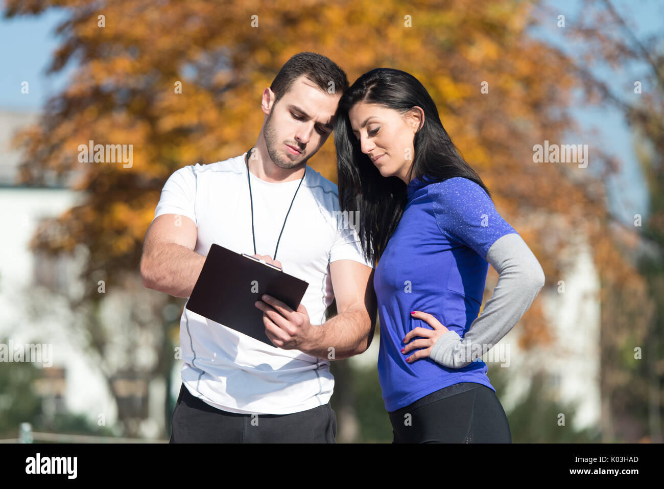 Personal Trainer Takes Notes While Young Woman Exercise in City Park ...