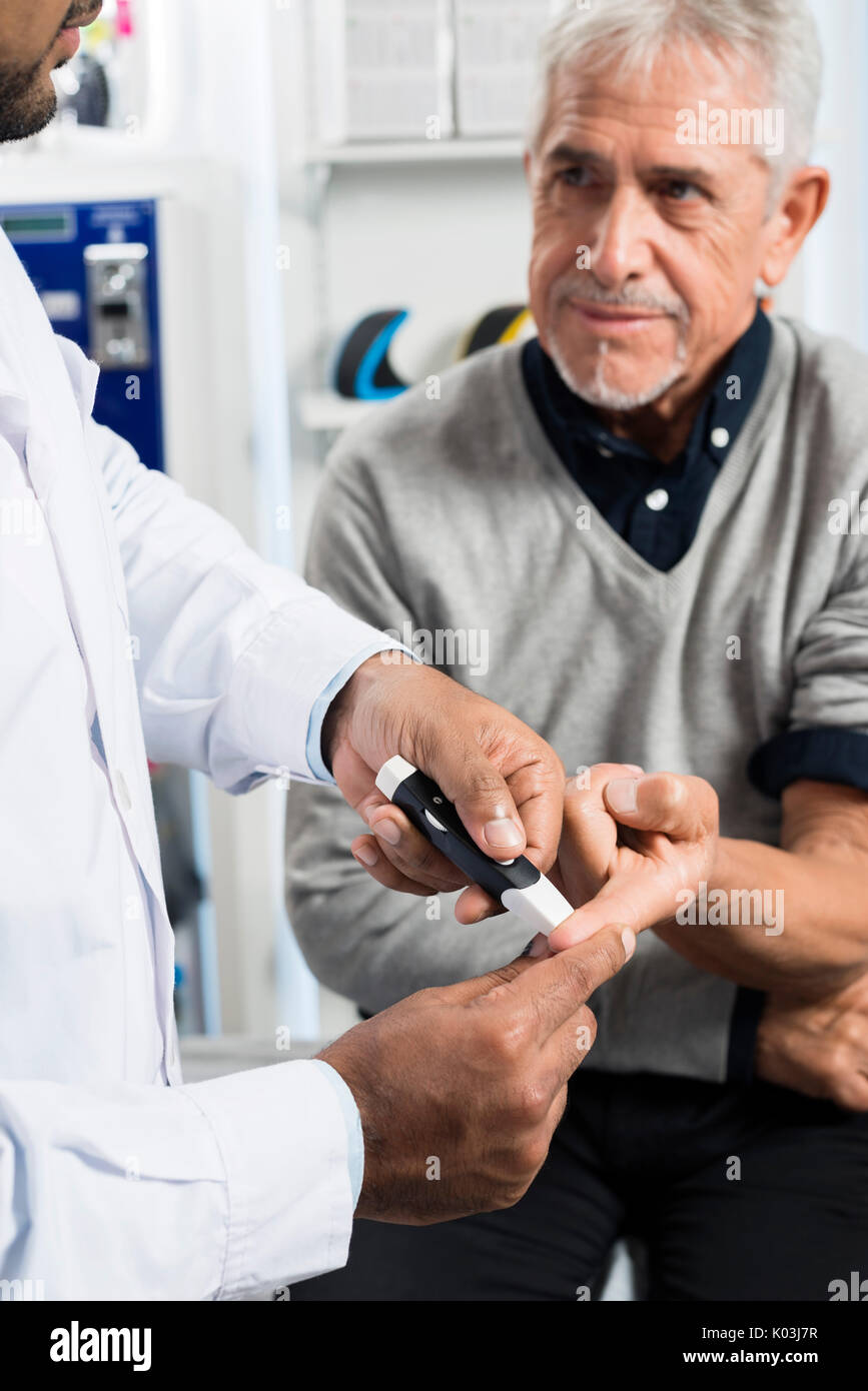 Male doctor checking patient's blood pressure while looking at machine ...