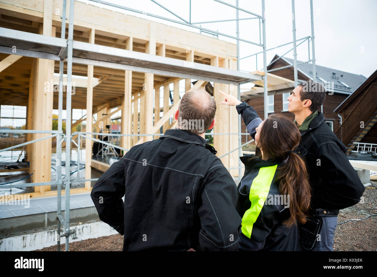 Female Carpenter Pointing At Incomplete Building While Standing Stock ...