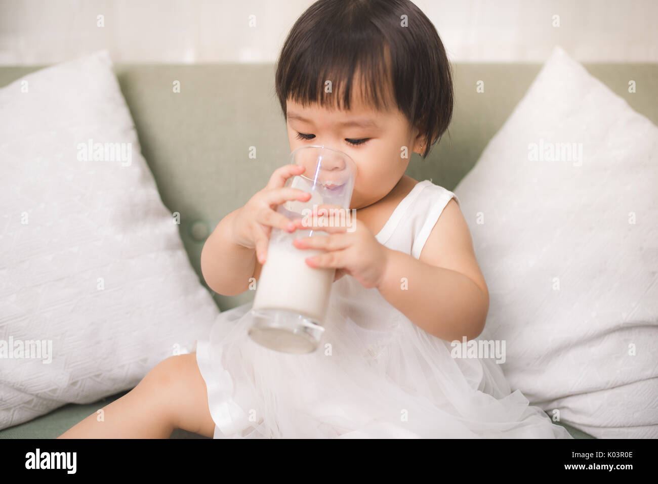 Cute baby girl drinking milk with milk mustache at home Stock Photo - Alamy