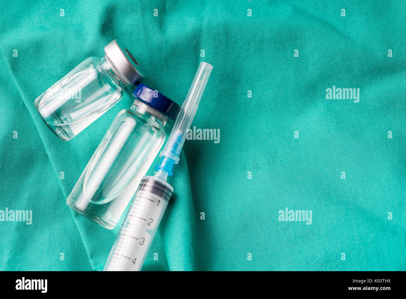 Medical syringe and vials lying on the hospital's green background. The ...