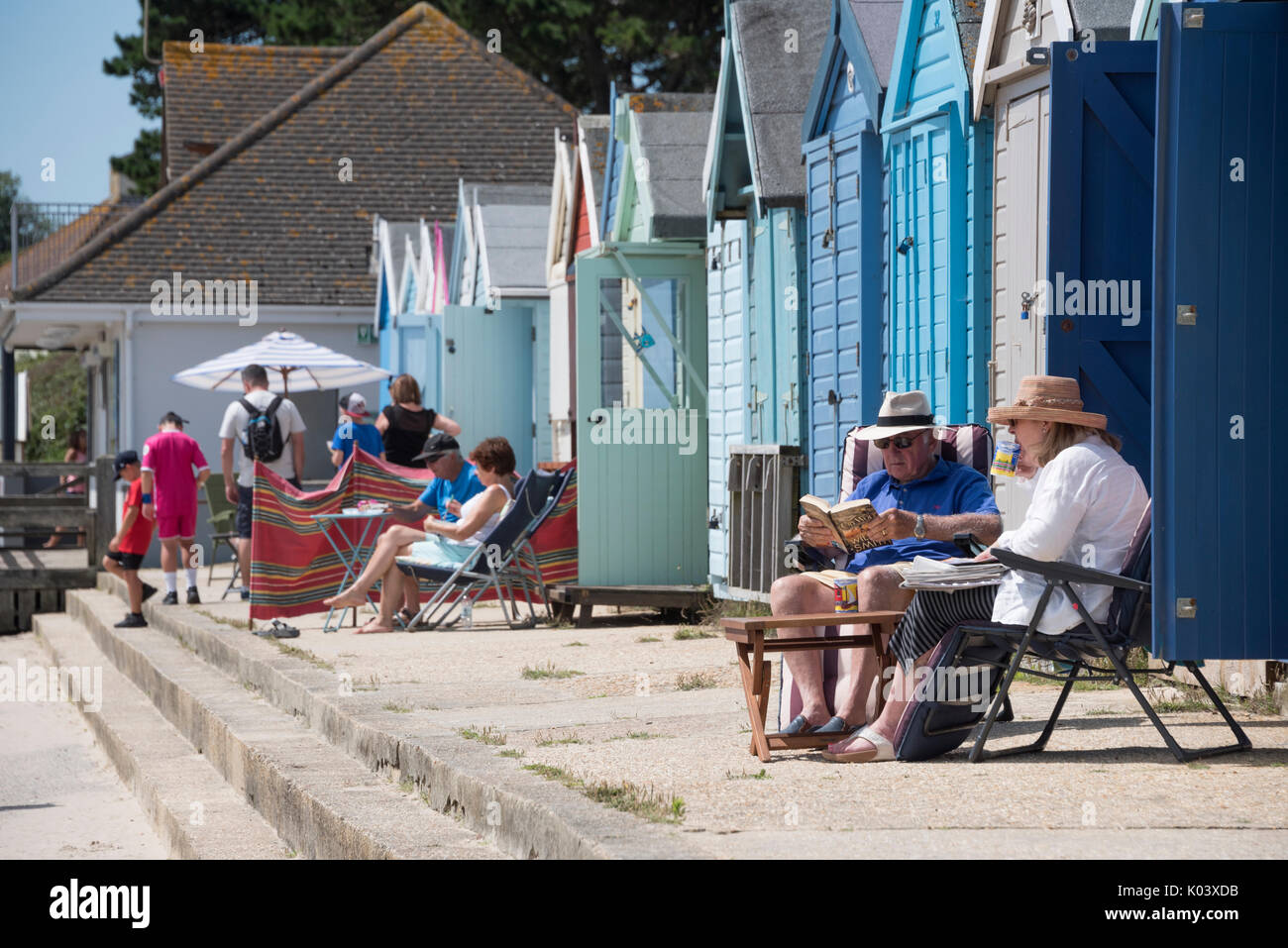 Enjoying the sun outside the beach huts at Friars Cliff, Christchurch ...