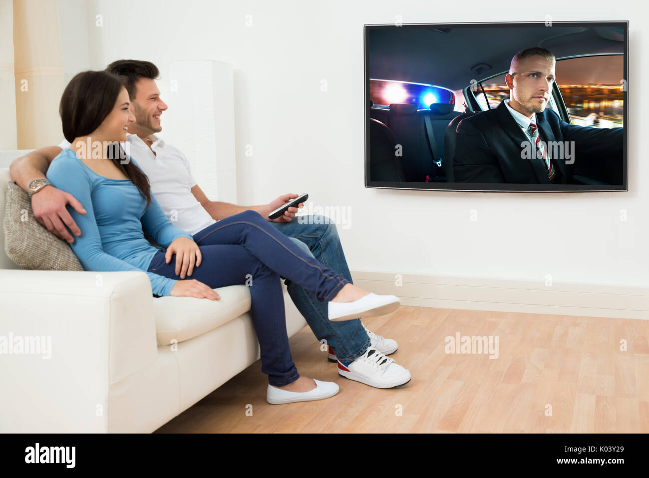 Happy Young Couple In Livingroom Sitting On Couch Watching Movie Stock ...
