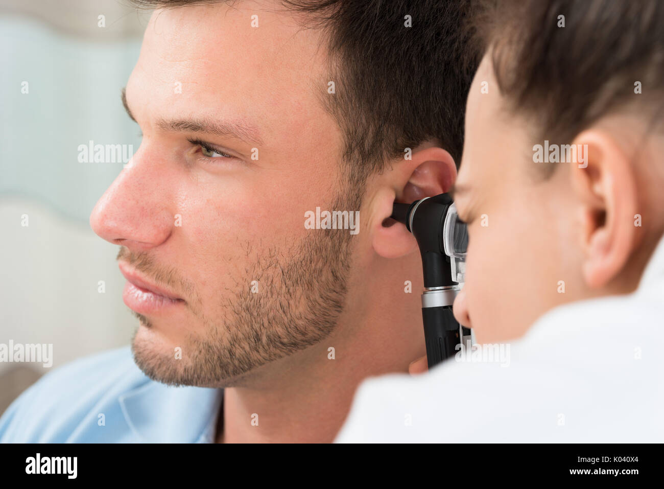 Physician Looking Into Male Patient's Ear With An Instrument Stock ...