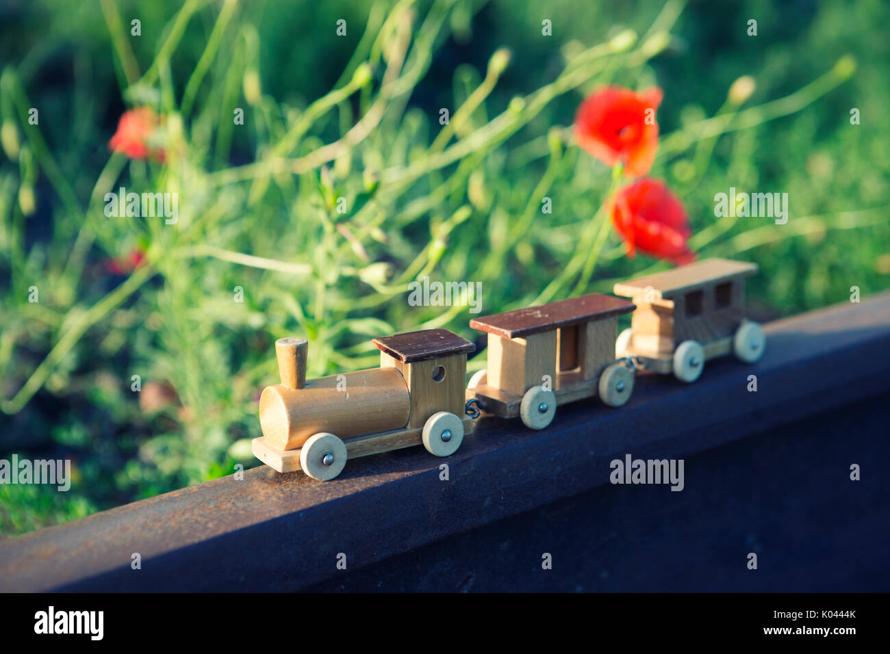 small wooden toy train on real railway tracks Stock Photo - Alamy
