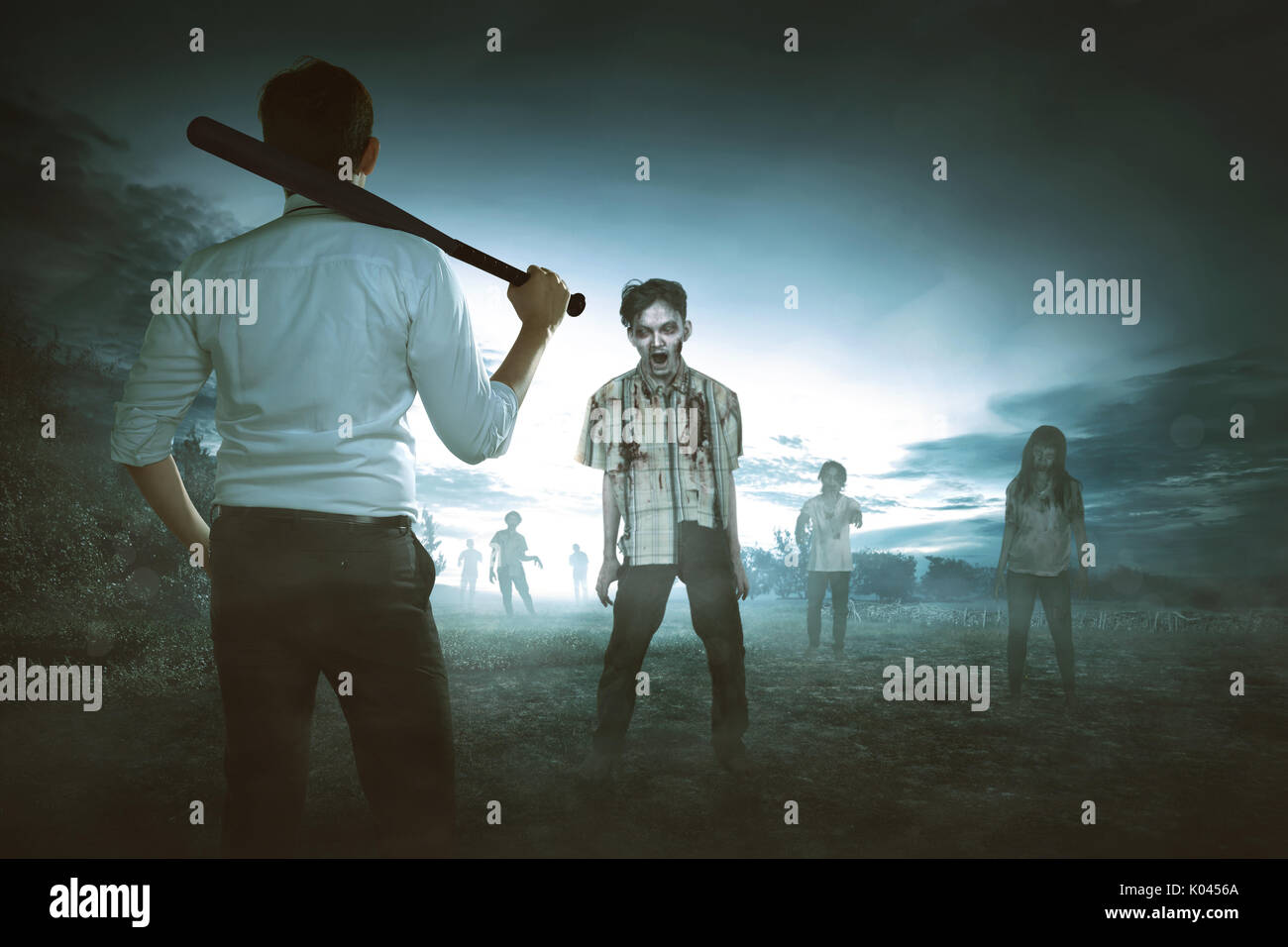 Back view of asian man holding baseball bat against zombies on the ...
