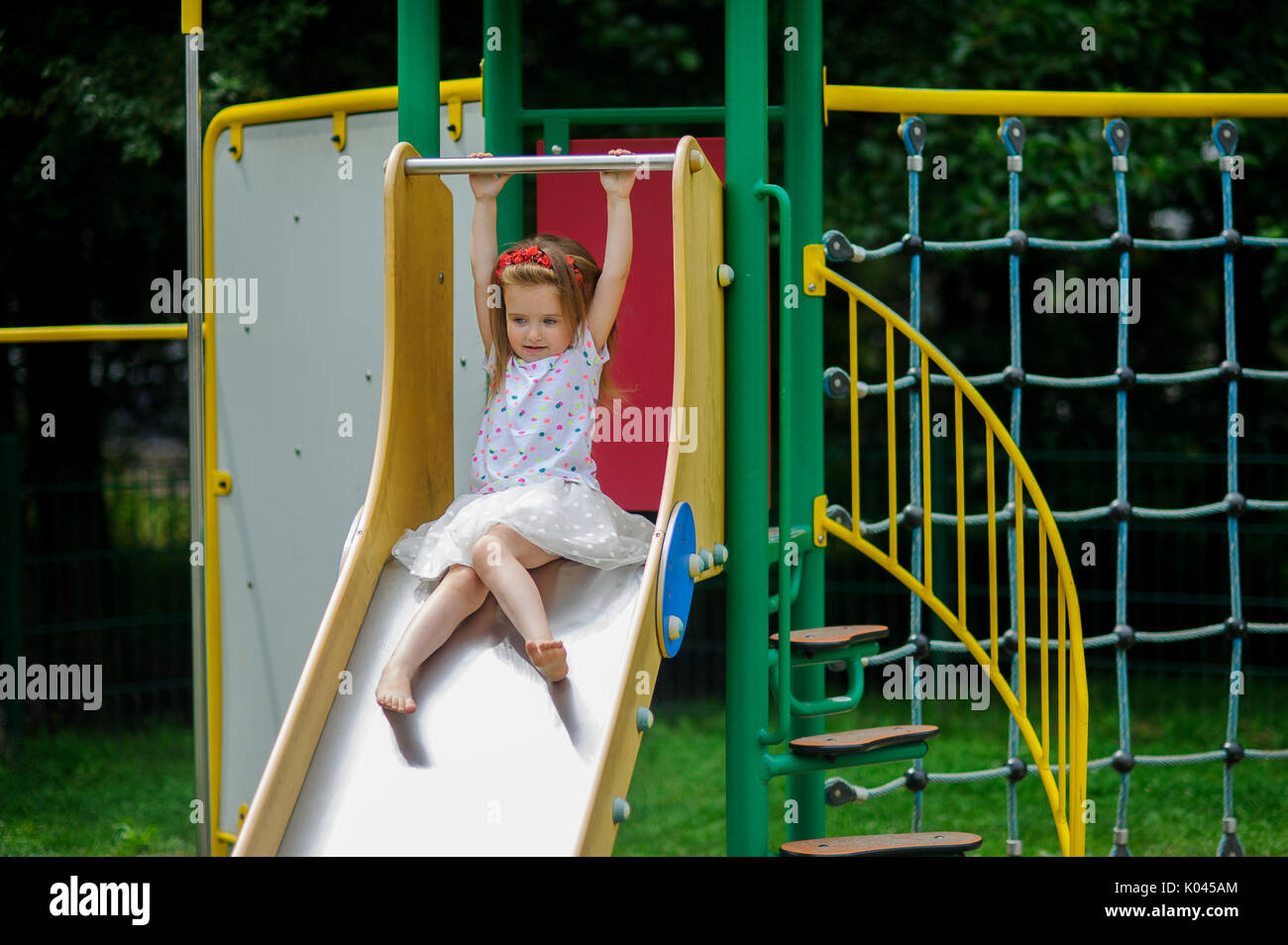 A cute little barefoot girly is playing on the playground. Baby is ...