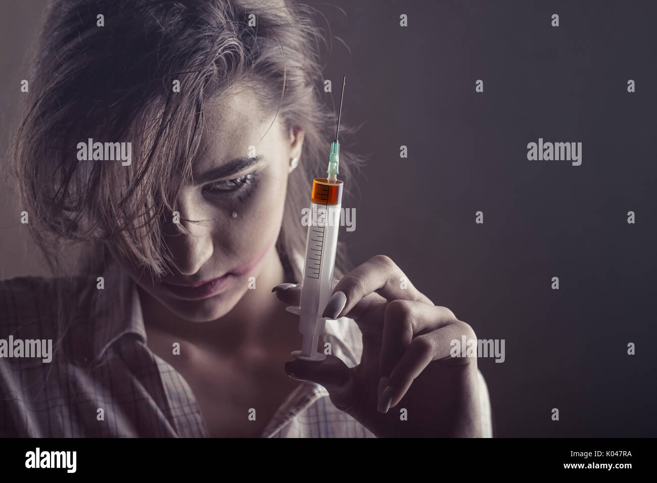 Young woman with drug addiction on dark background. Focus on syringe ...