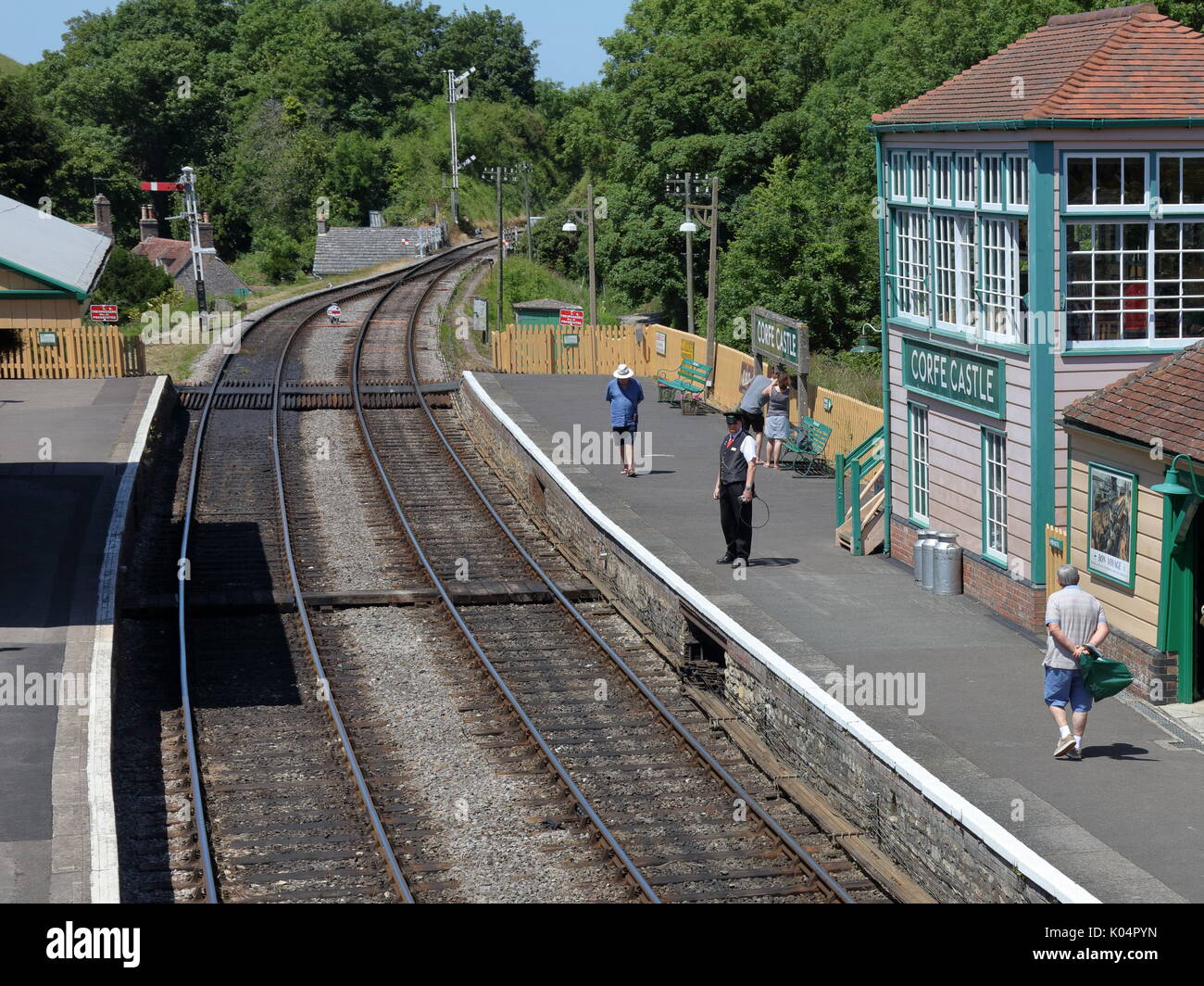 Heritage steam railway station and guard awaiting train with single ...