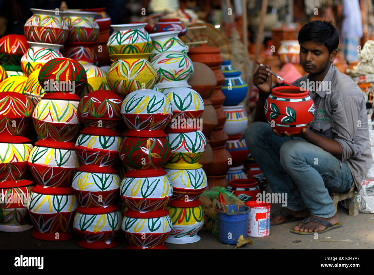 An artist paints on clay potteries at a road-side shop in Dhaka ...