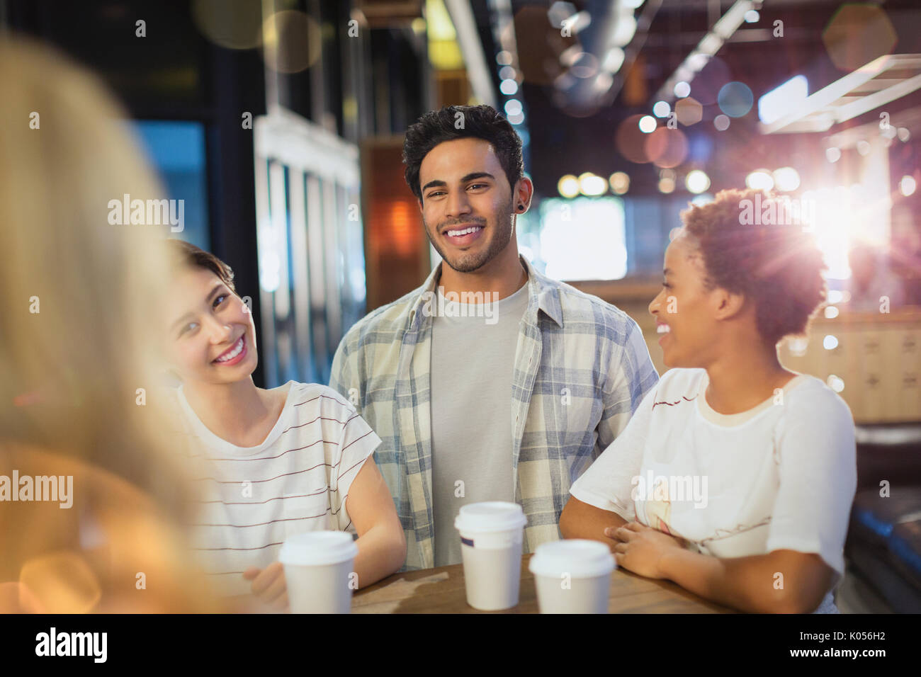 Smiling young friends drinking coffee at cafe Stock Photo - Alamy