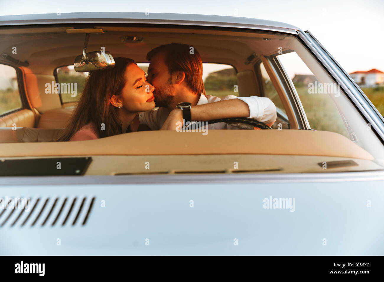 Young happy couple kissing while sitting together inside a car. Front ...