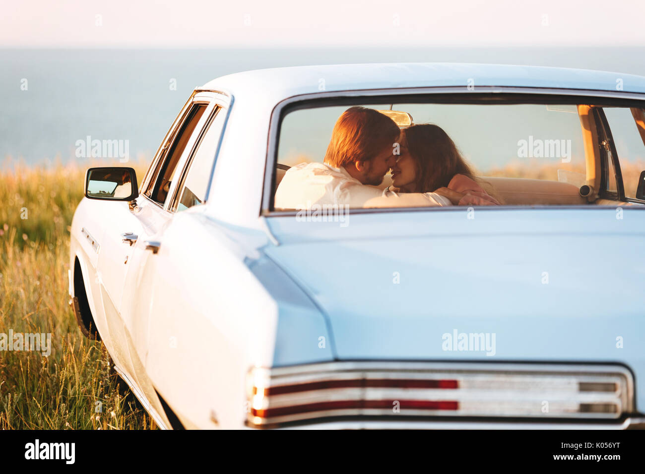 Back view of a smiling attractive couple in love sitting and kissing on ...