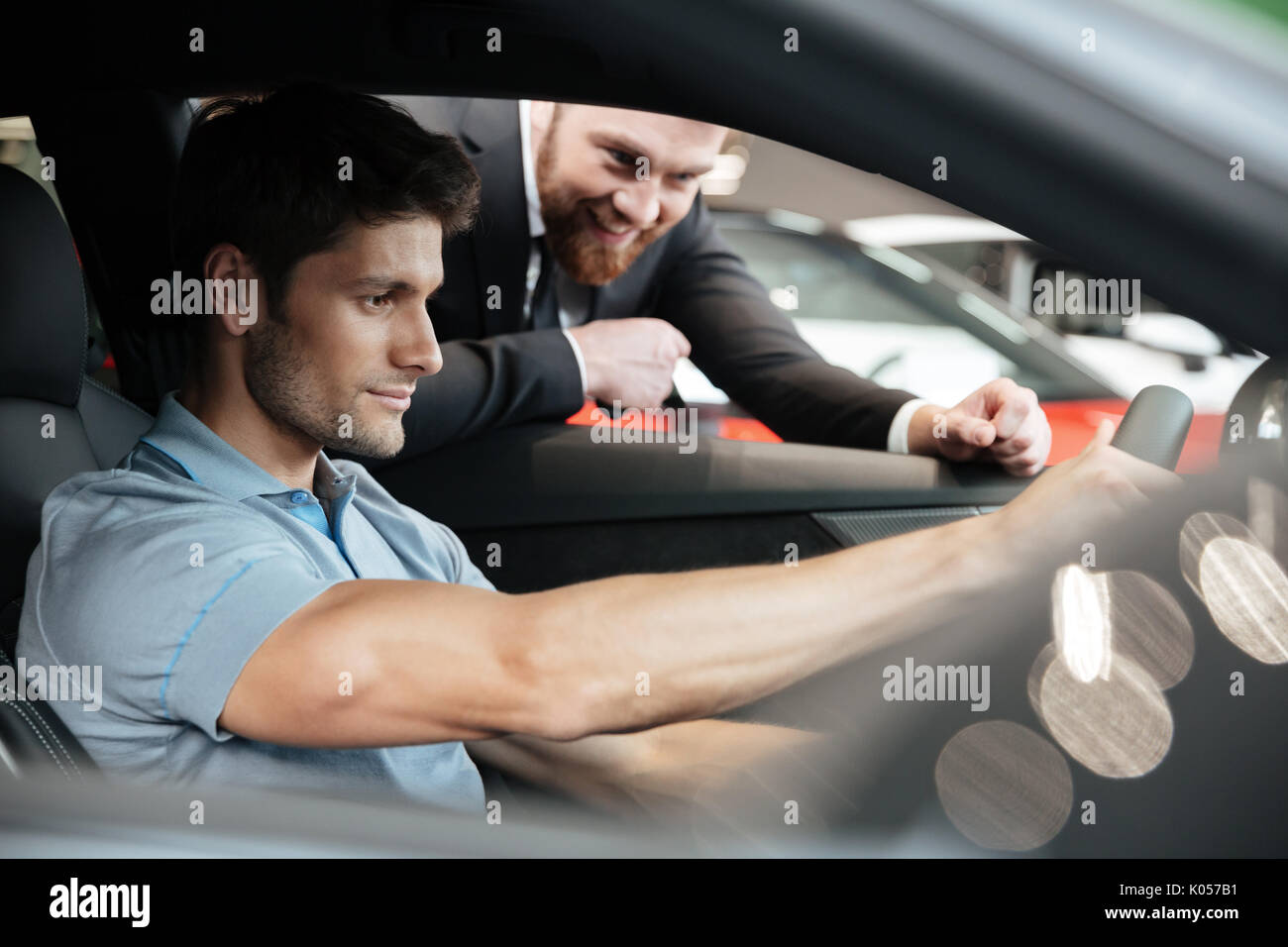Young man testing a new car with a salesperson at the dealership Stock ...