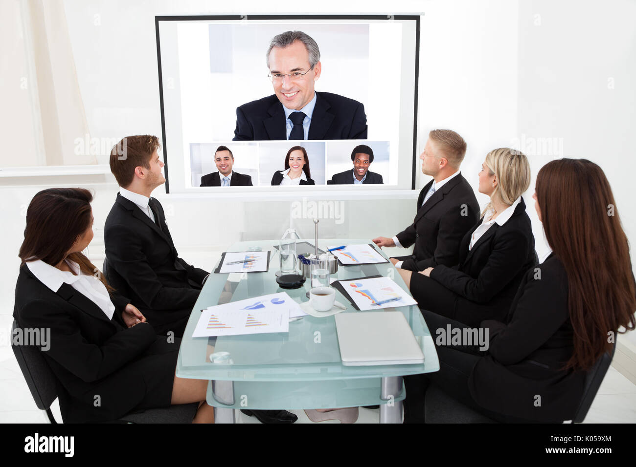 Businesspeople looking at projector screen in video conference meeting ...