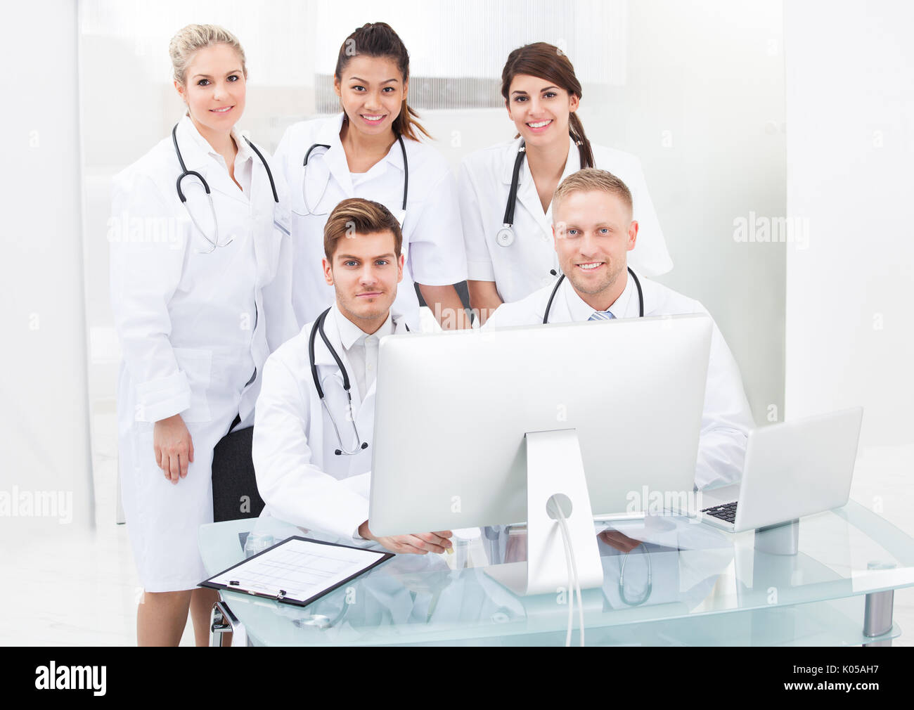 Team of doctors using desktop PC together at desk in clinic Stock Photo ...