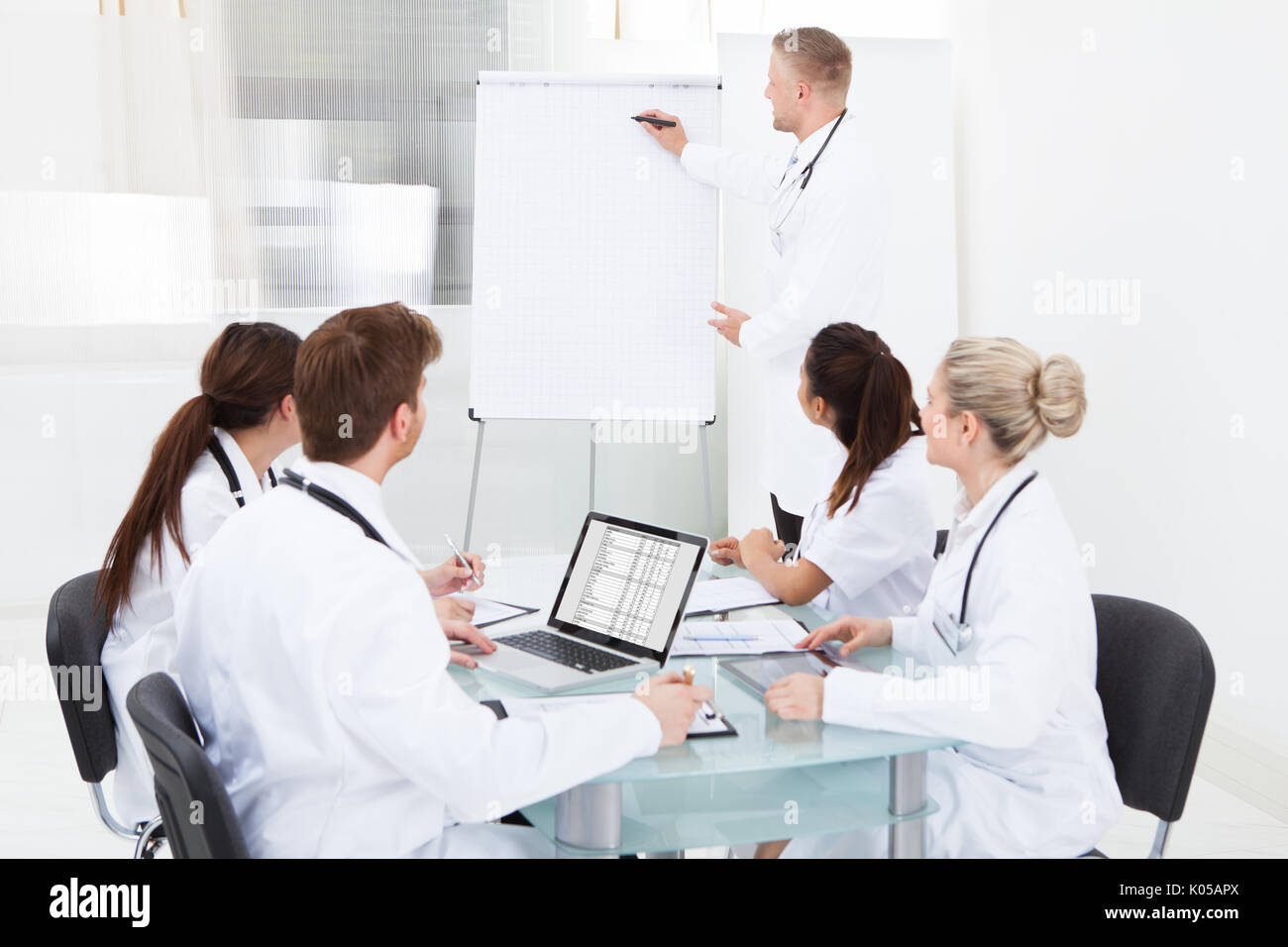Male doctor giving presentation on flipchart to colleagues in hospital ...