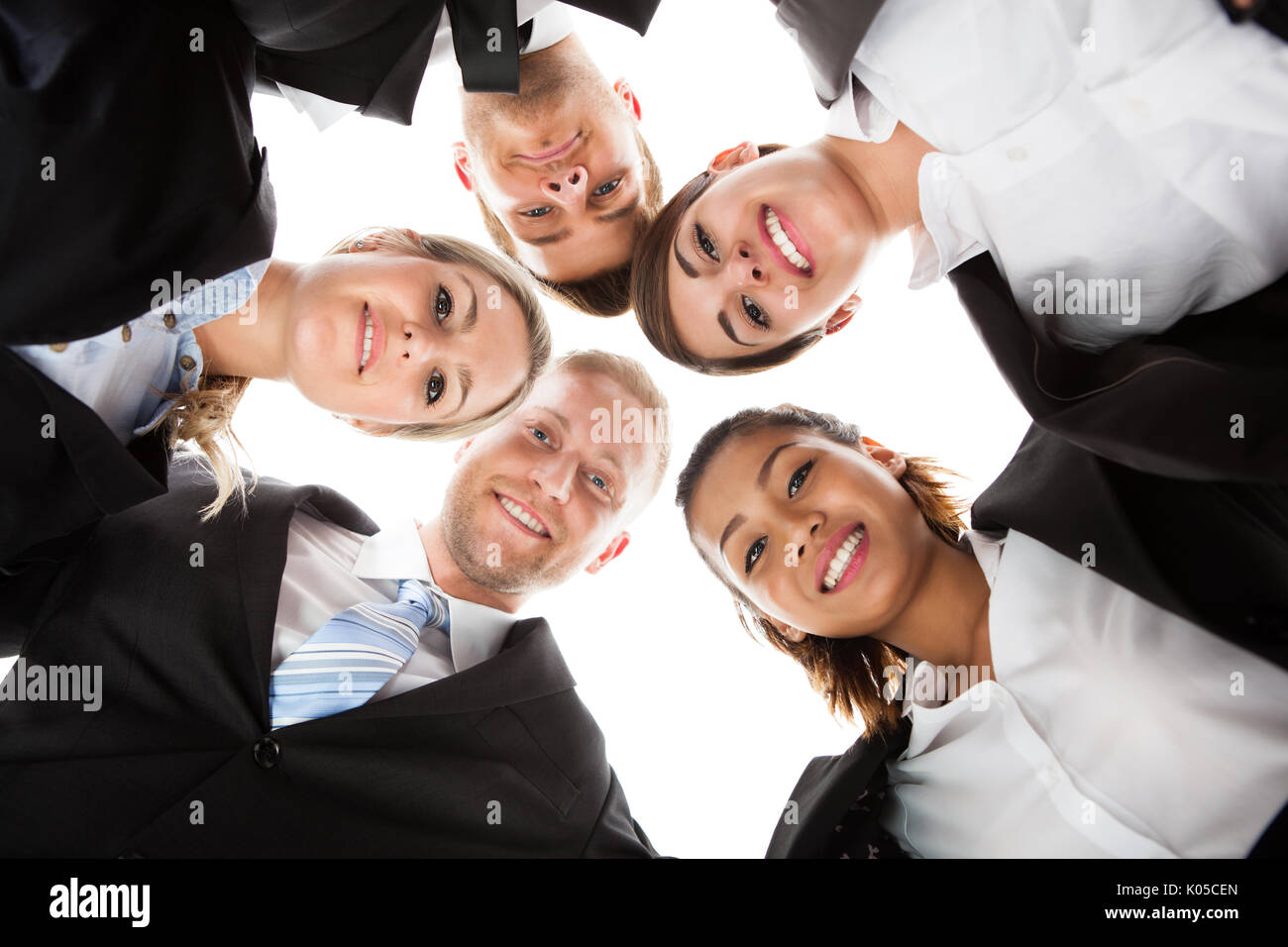 Low angle portrait of business people forming huddle against white ...