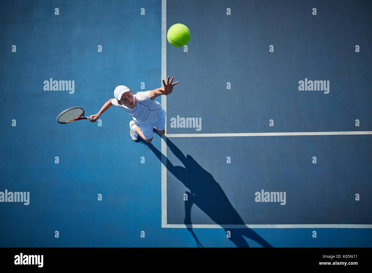Overhead view of young male tennis player playing tennis, serving the ...