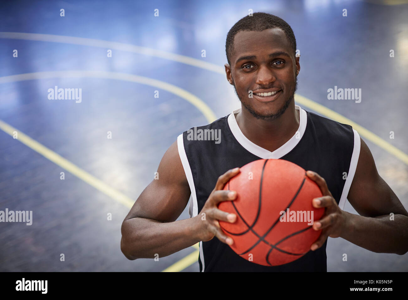 Portrait smiling young male basketball player holding basketball on ...
